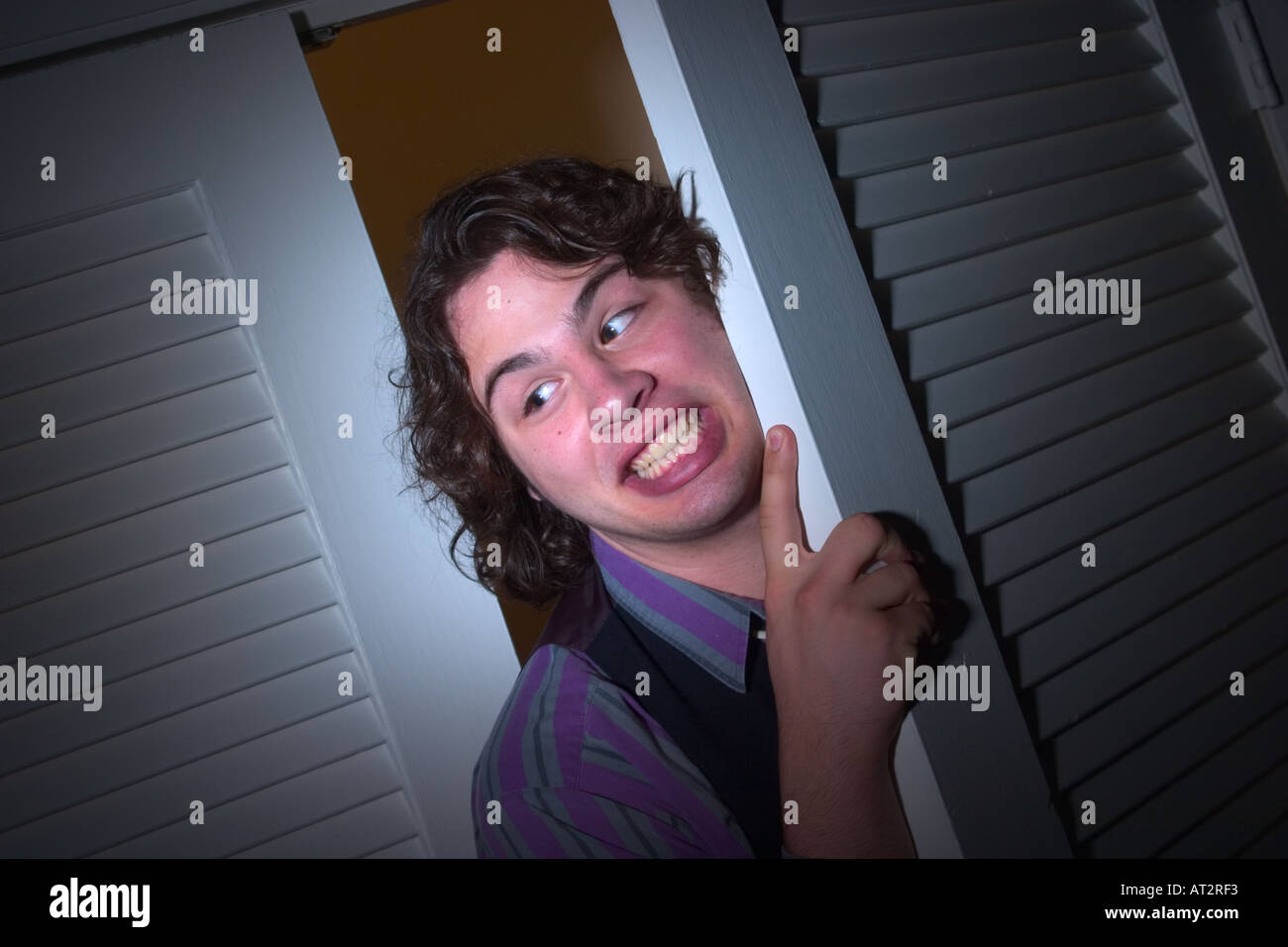 Teen boy sticking his head out the door from inside a closet at his ...