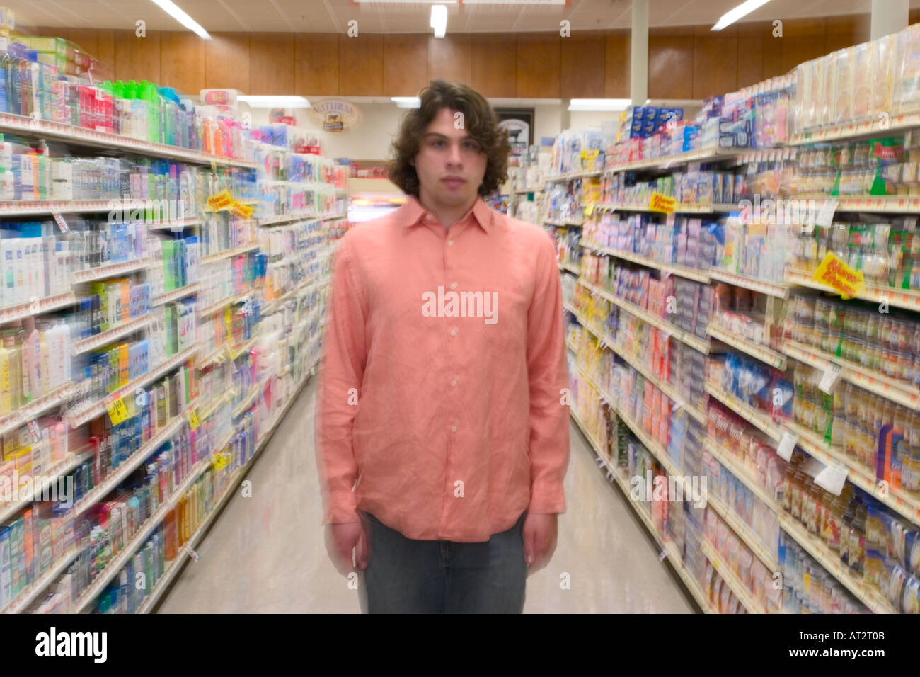 Teen boy standing in the middle of a food aisle at a grocery store ...