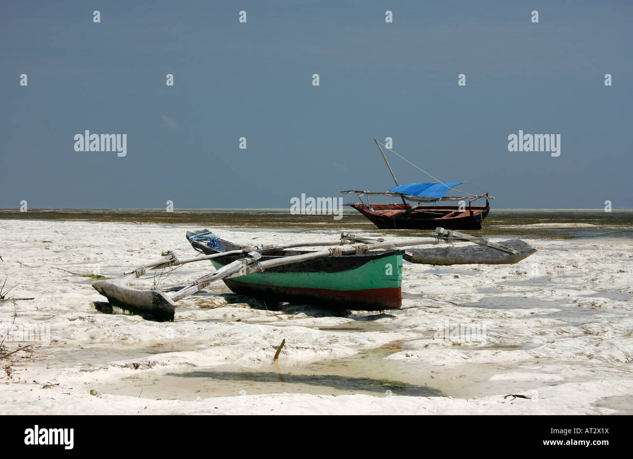 An outrigger canoe (ngalawa) and a small dhow stranded on the beach at ...