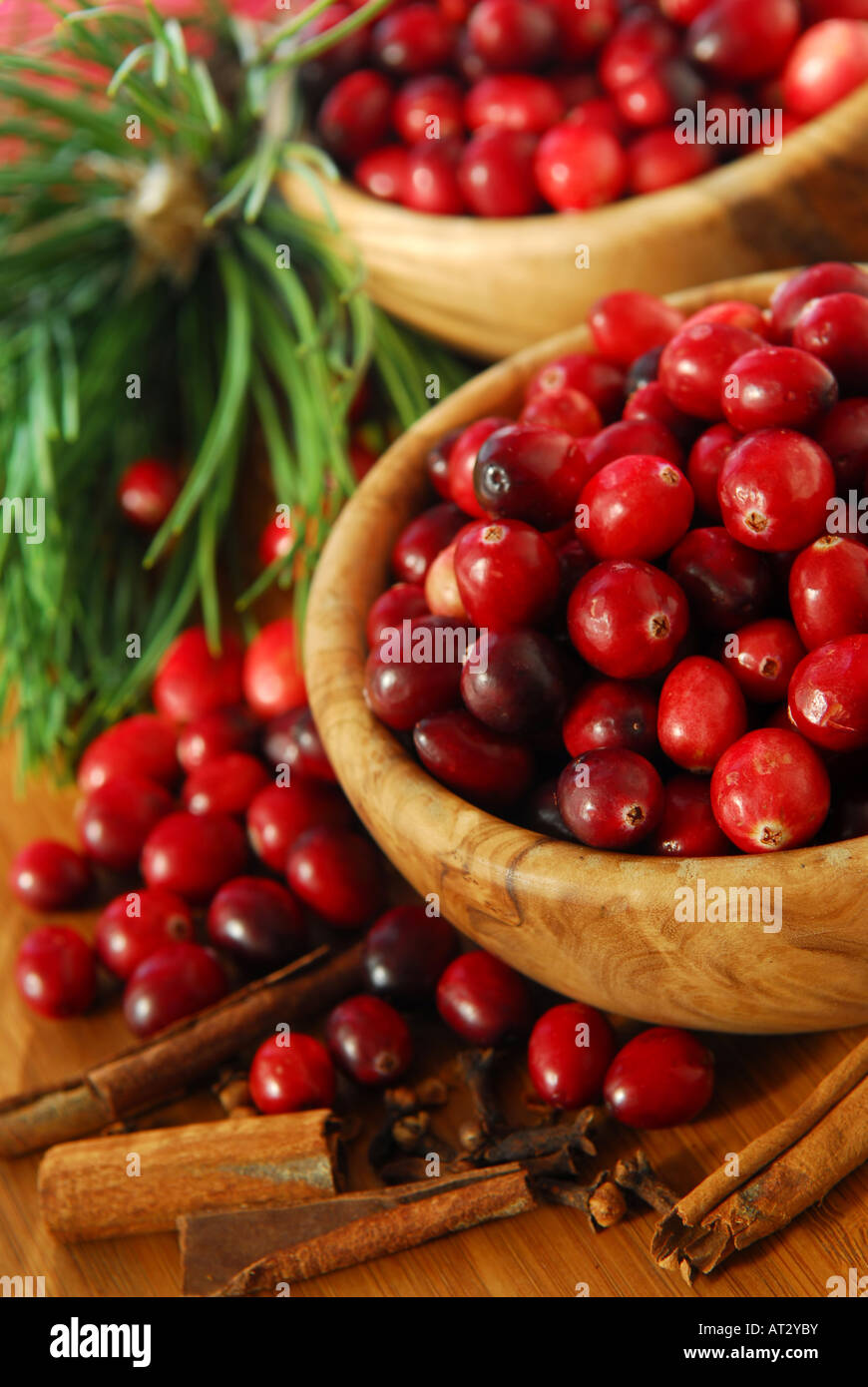 Fresh red cranberries in wooden bowls with spices and pine branches ...