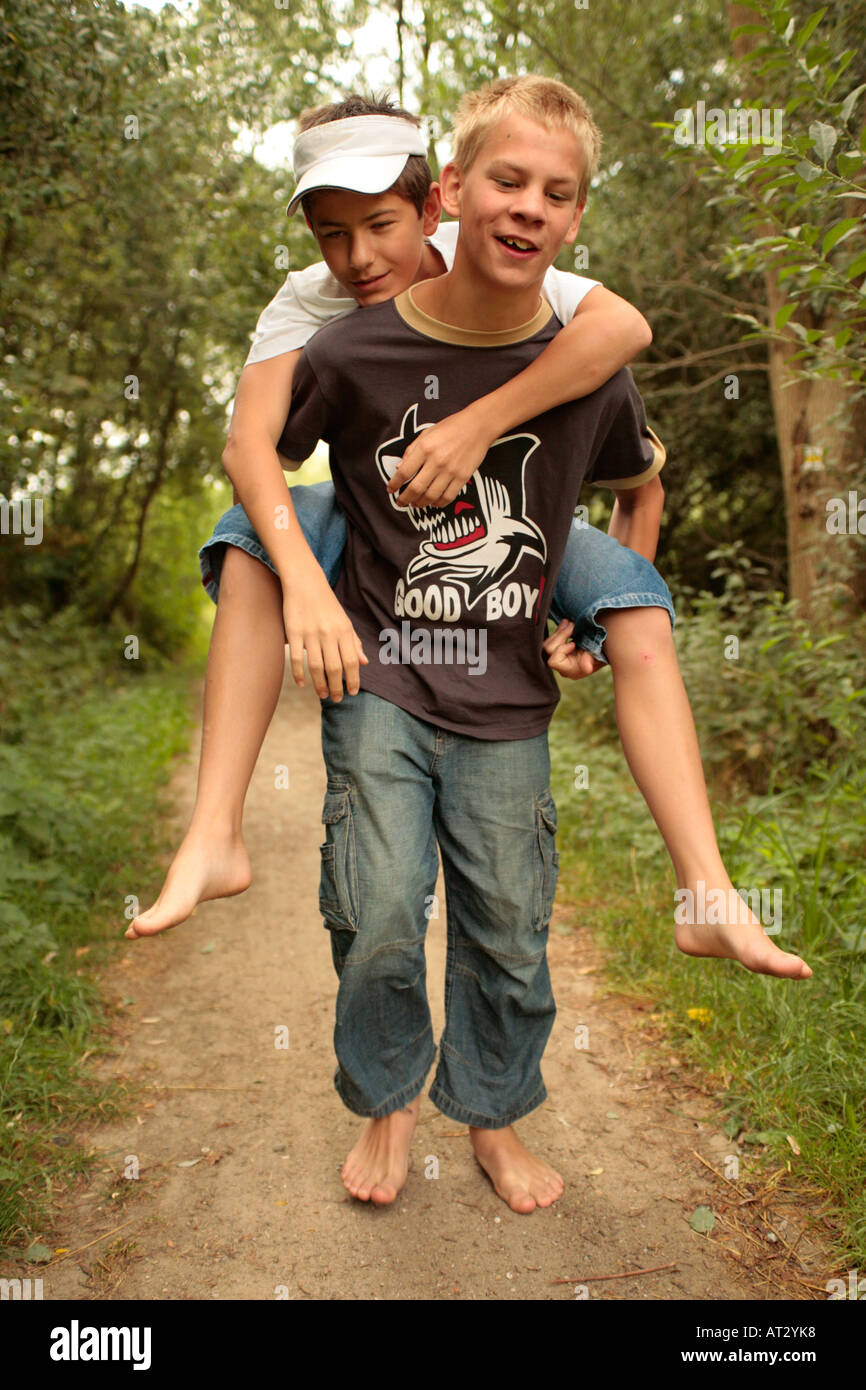 a young boy is carrying his exhausted friend on his back Stock Photo ...