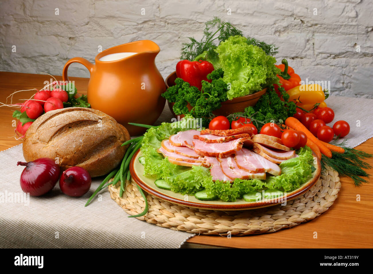 Ham cold meats platter with assorted vegetables bread and jug with milk ...