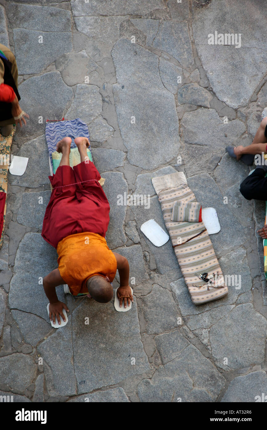 Buddhist monk and pilgrims prostrate in prayer outside the Jokhang ...