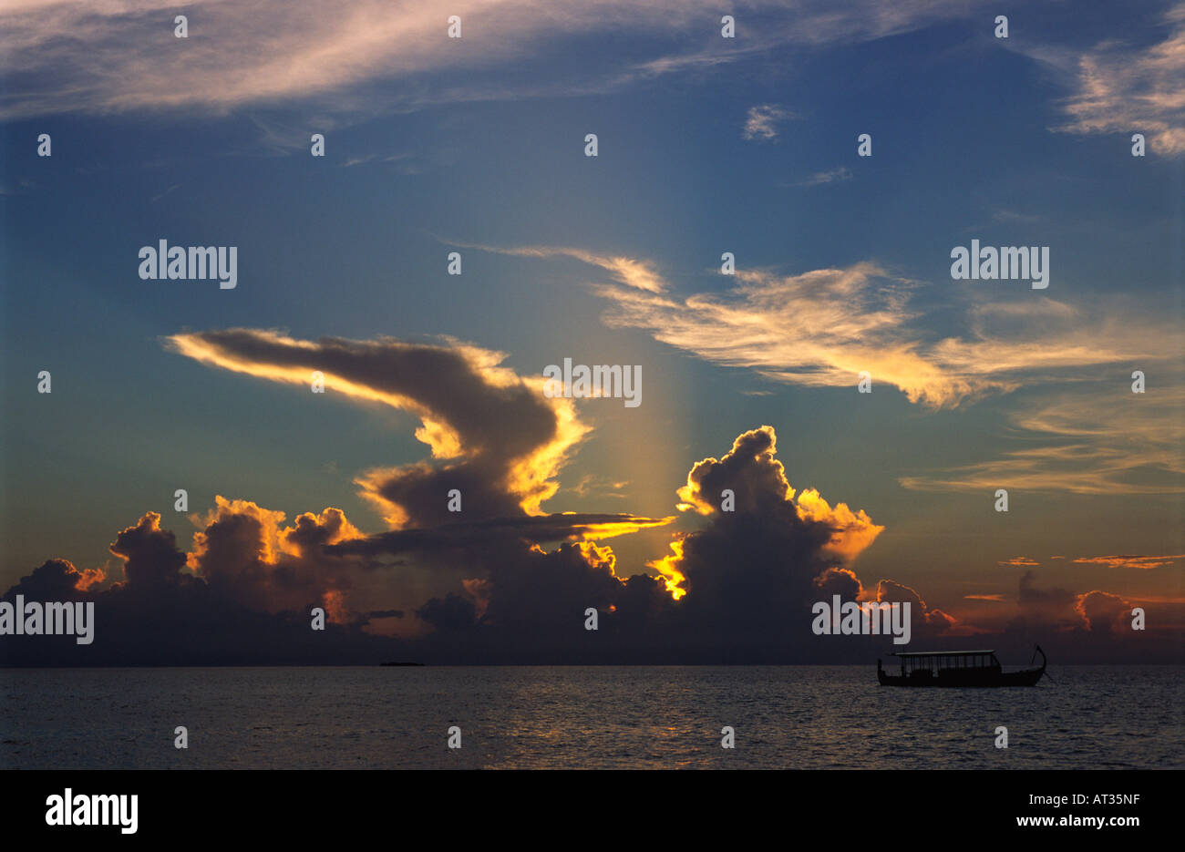 Sunset in the Maldives with cloud formations and dhoni dive boat in the ...