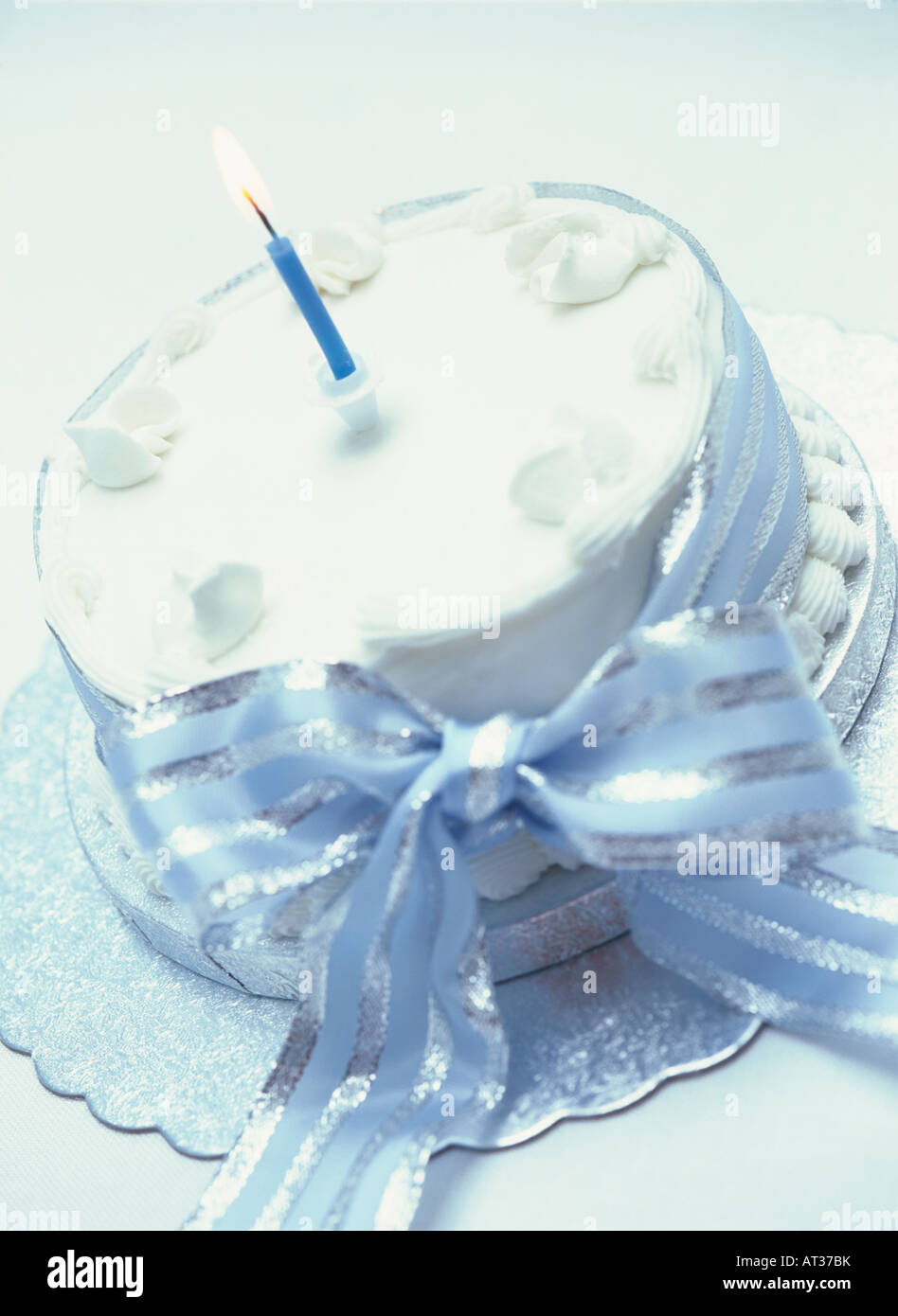 A white celebration cake with a single blue candle on top Stock Photo ...