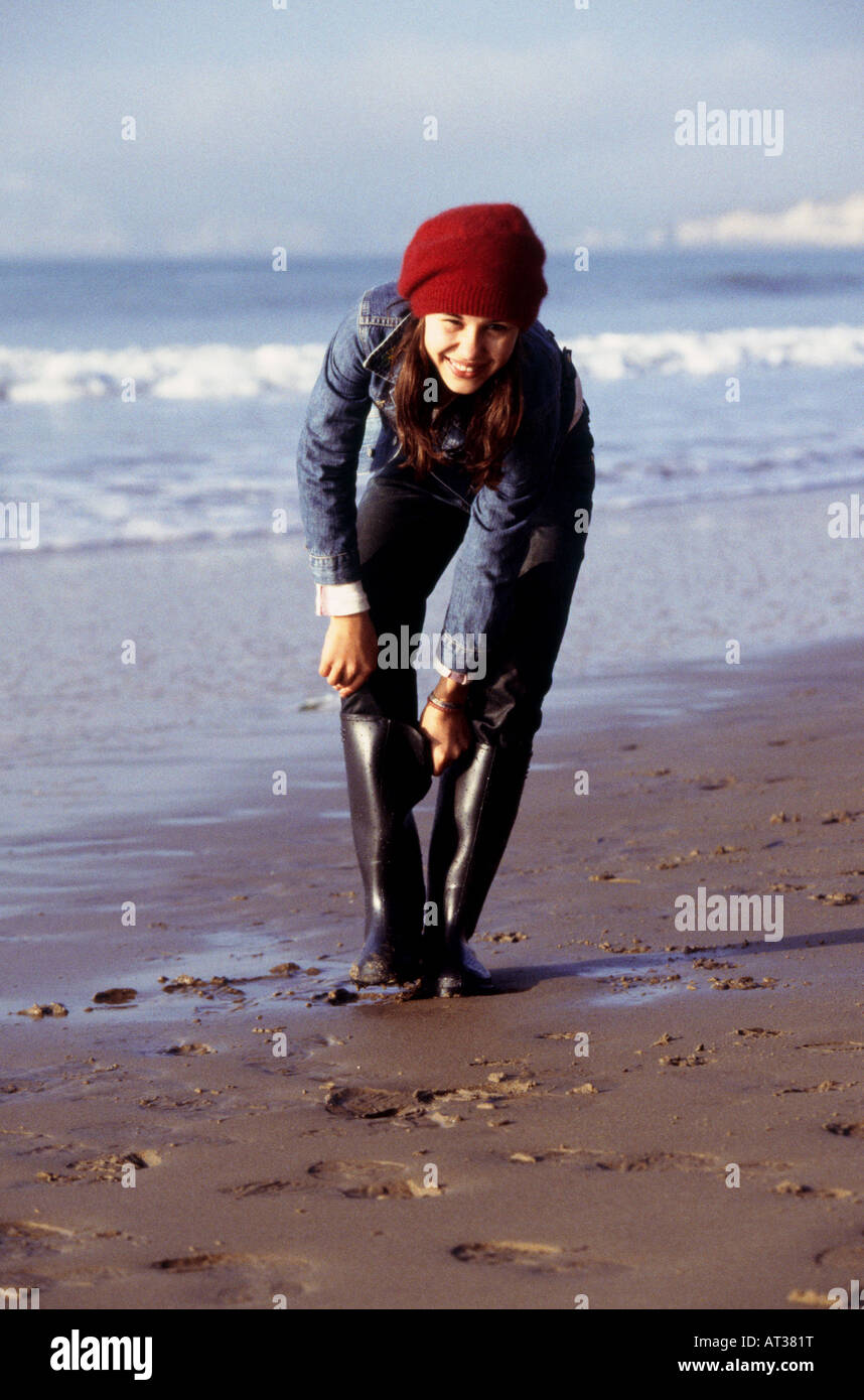 A girl on a beach taking off/putting on her boots Stock Photo - Alamy