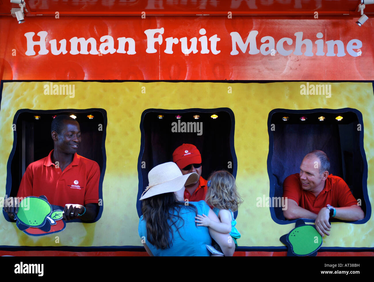 A MOTHER WITH HER CHILD COLLECTS HER PRIZE FROM A HUMAN FRUIT MACHINE ...
