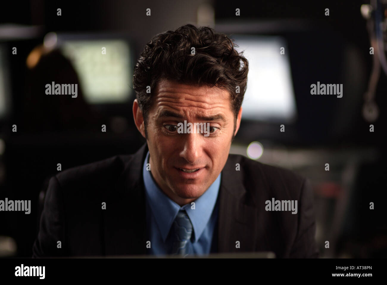 A business man looking at his computer with a concerned expression ...