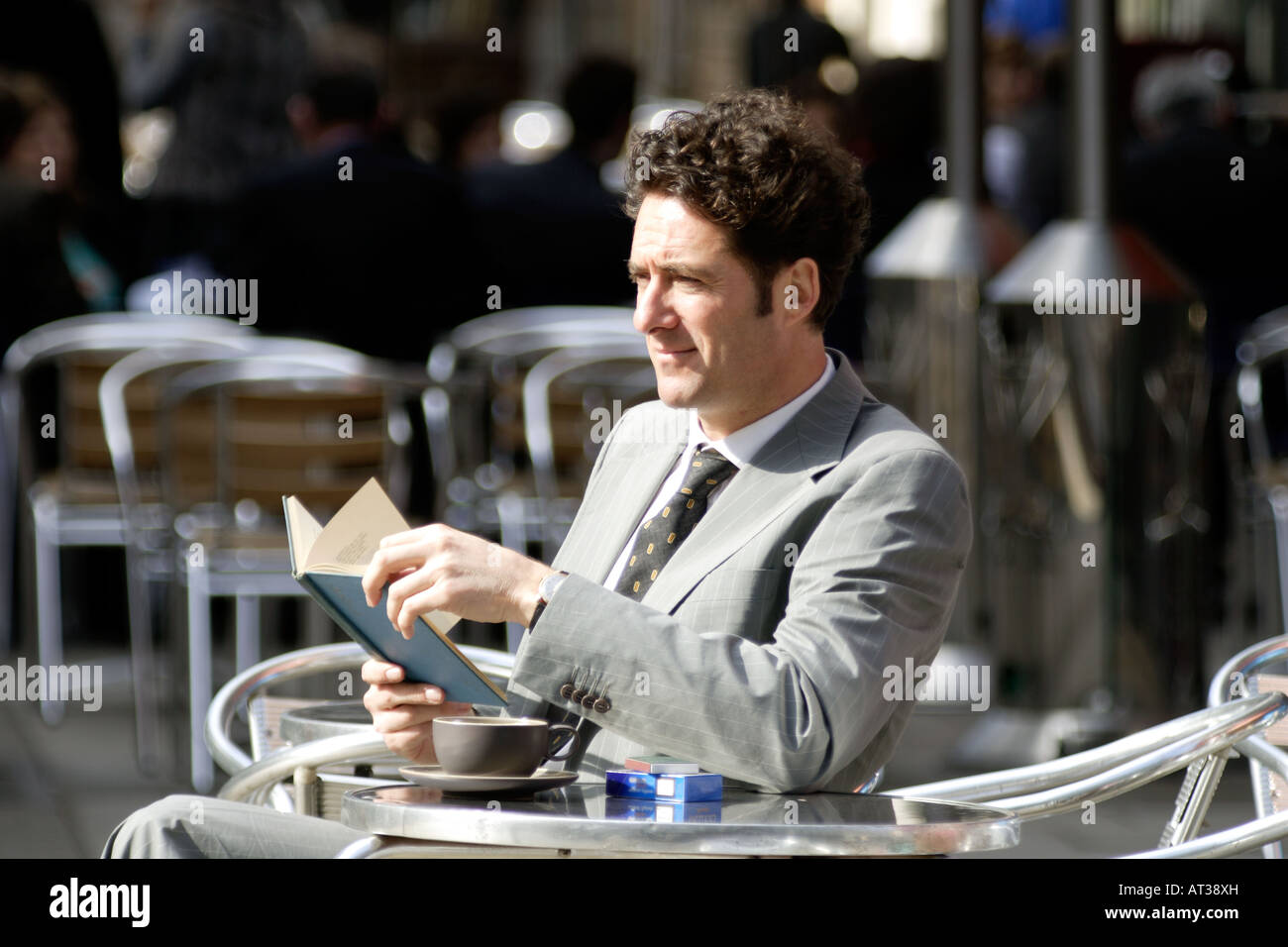 A man sitting outside a café reading a book Stock Photo - Alamy