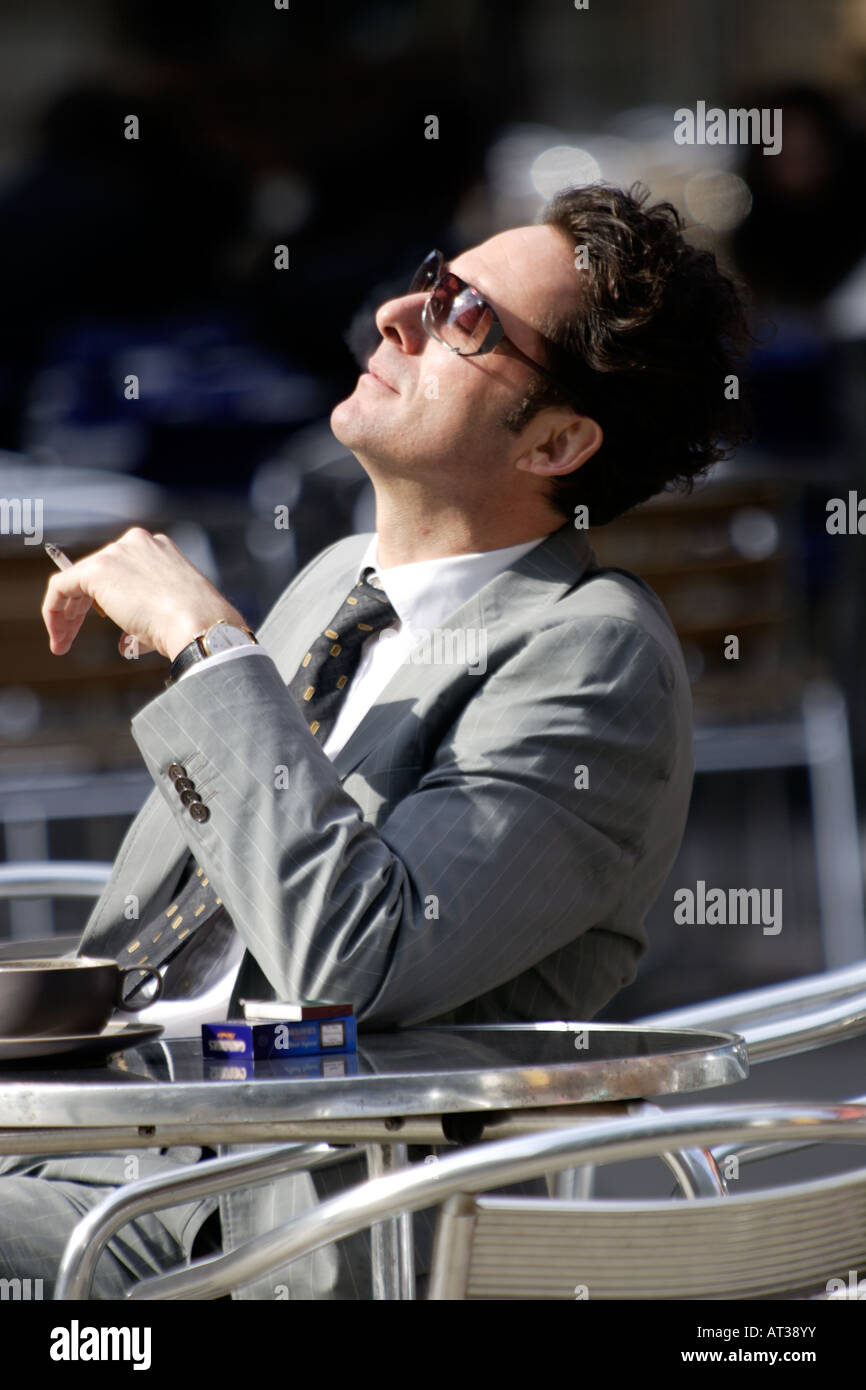 A man sitting outside a café in the sunshine smoking a cigarette Stock ...