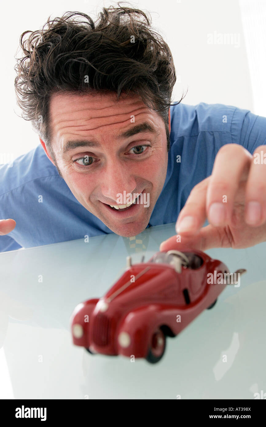A man playing with a red toy car Stock Photo - Alamy