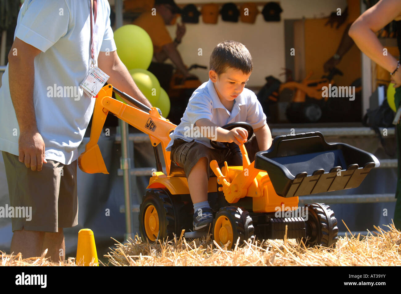 A FATHER HELPS HIS CHILD PLAY ON A TOY DIGGER AT THE INNOCENT VILLAGE ...