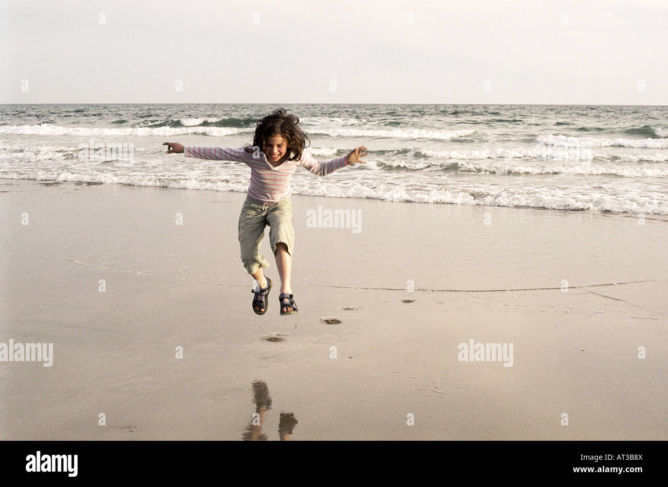 A young girl jumping up and down on the beach Stock Photo - Alamy