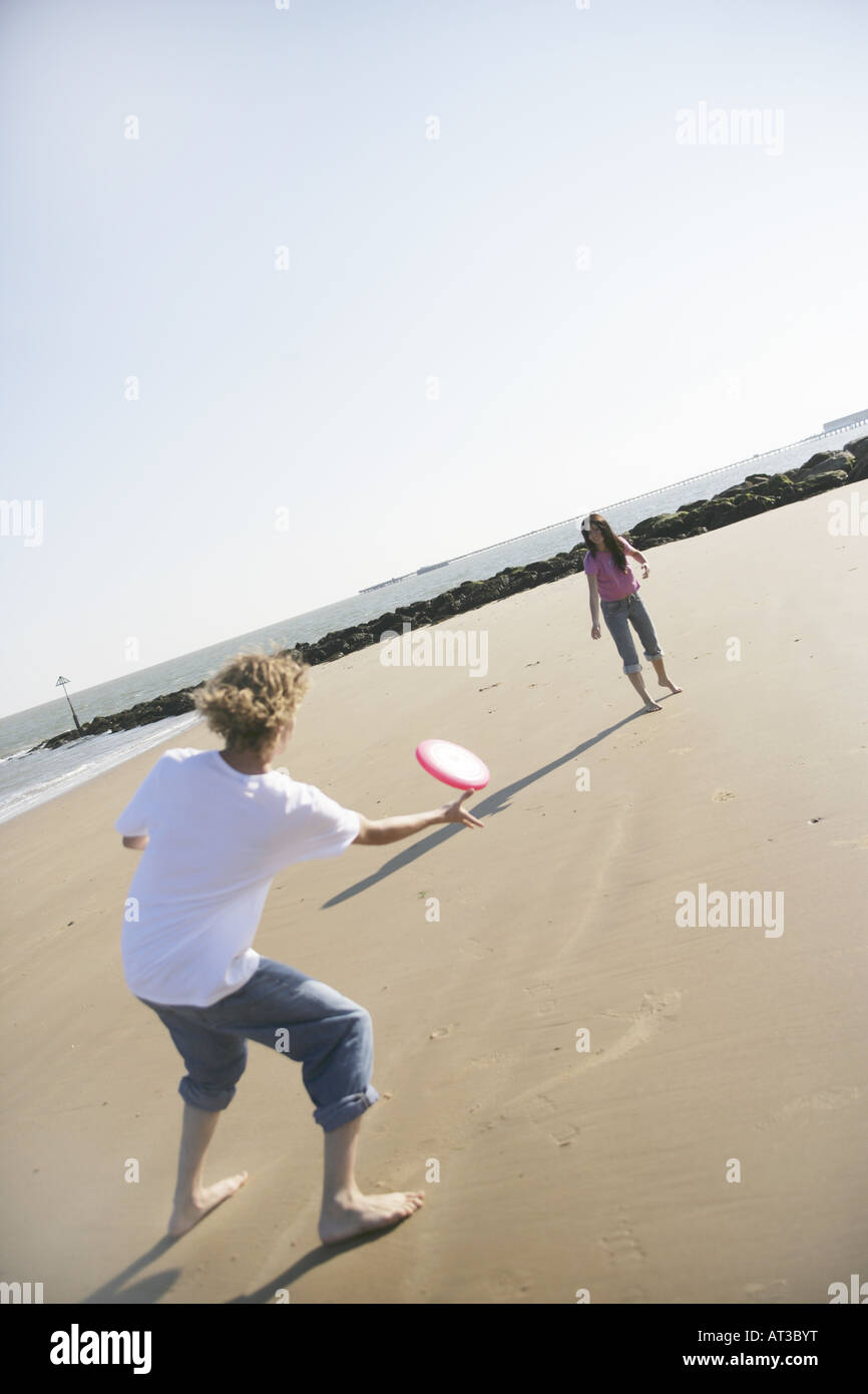 A young couple playing frizbee on the beach Stock Photo - Alamy