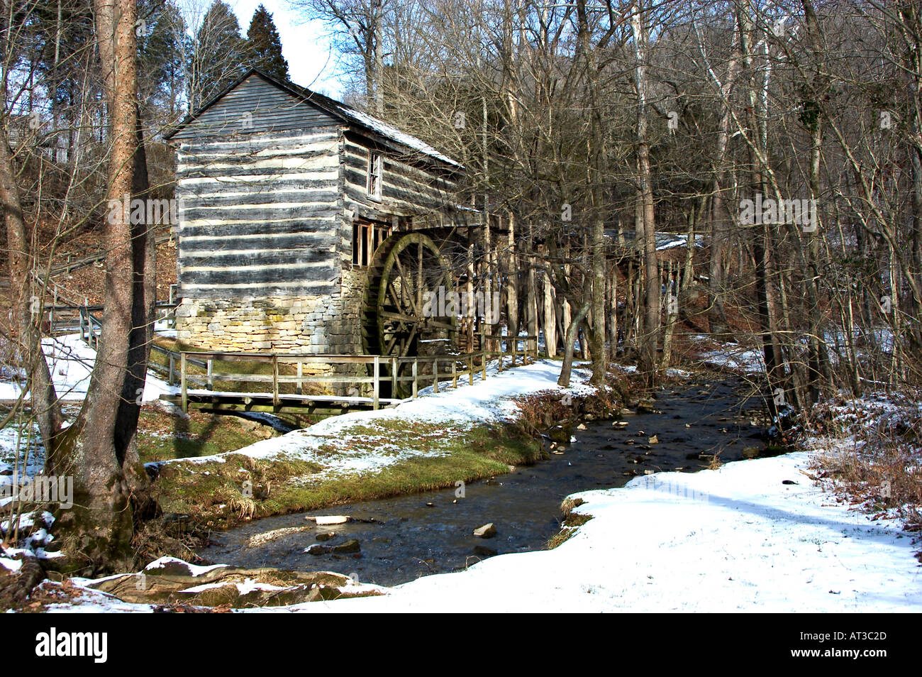 Historic grist mill next to stream with water wheel in winter with snow ...