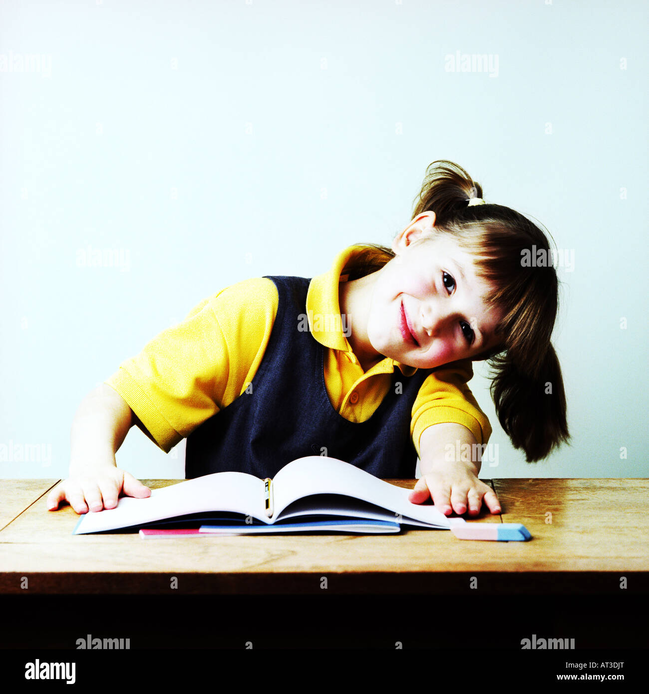 A school girl writing at a desk looking happy Stock Photo - Alamy