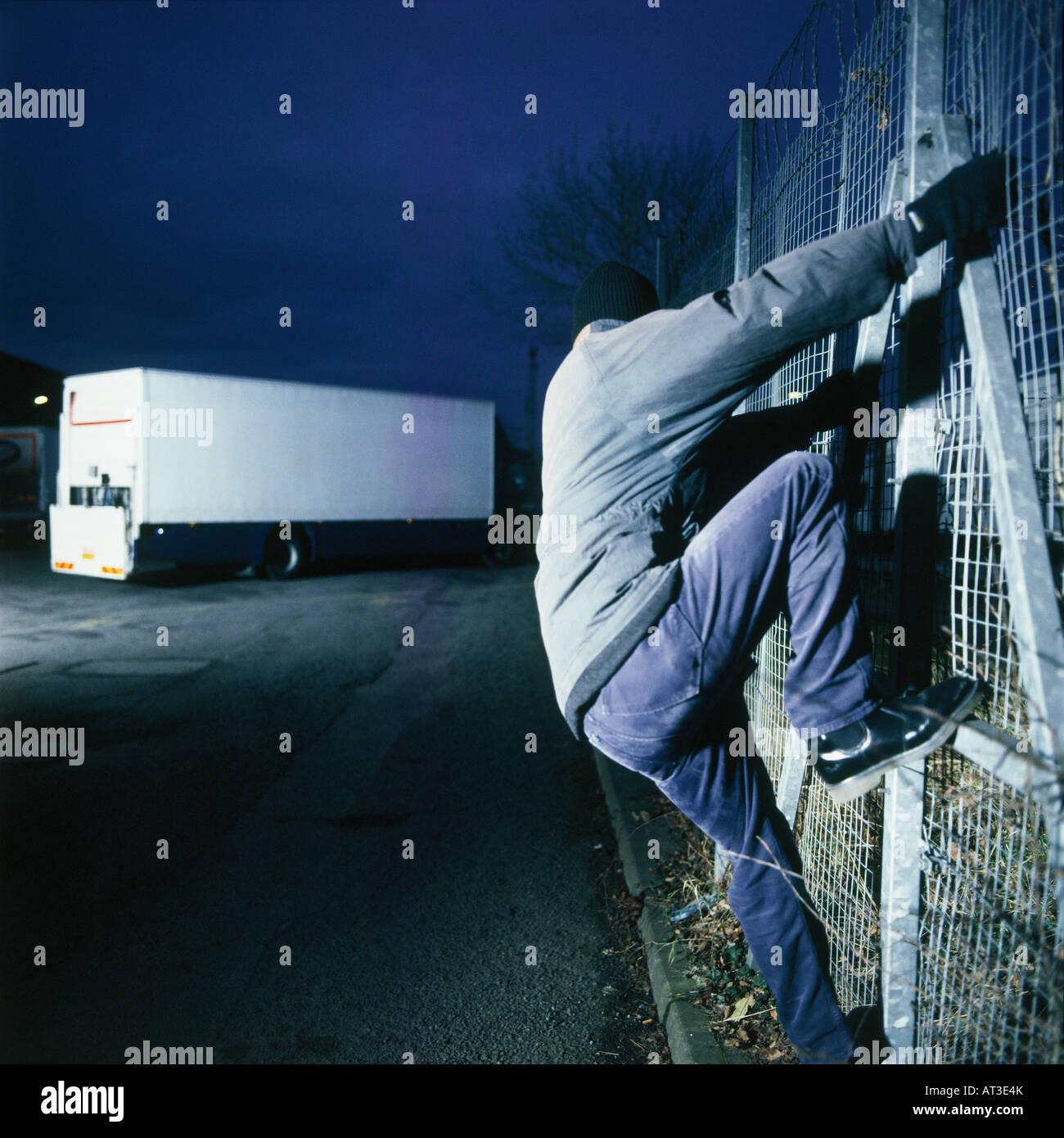 A burglar climbing a wire fence Stock Photo - Alamy