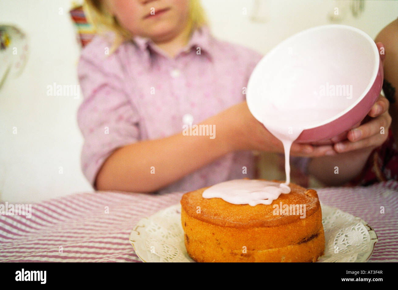 A young girl pouring icing on a cake Stock Photo - Alamy