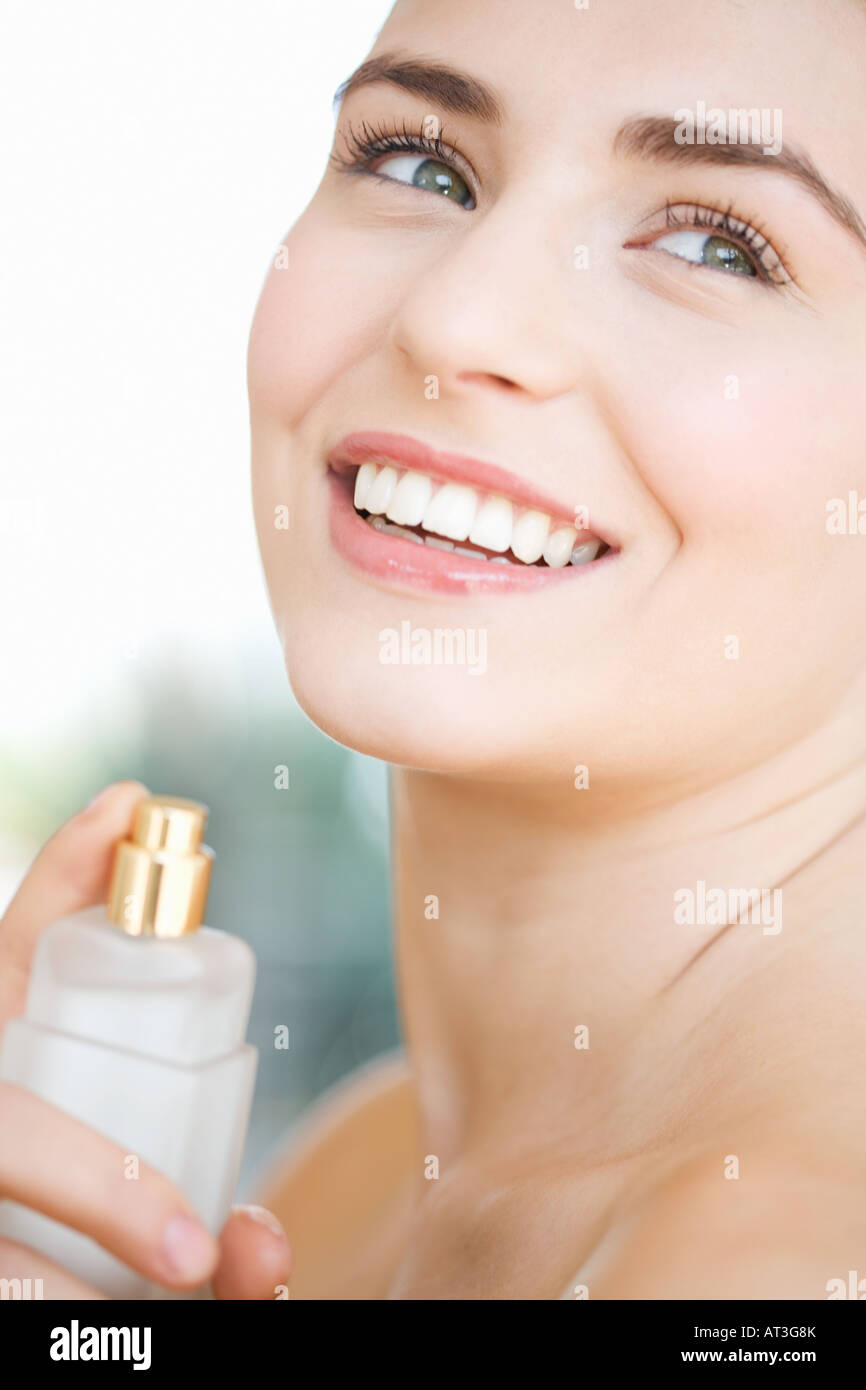 Woman spraying perfume on her neck, smiling Stock Photo - Alamy