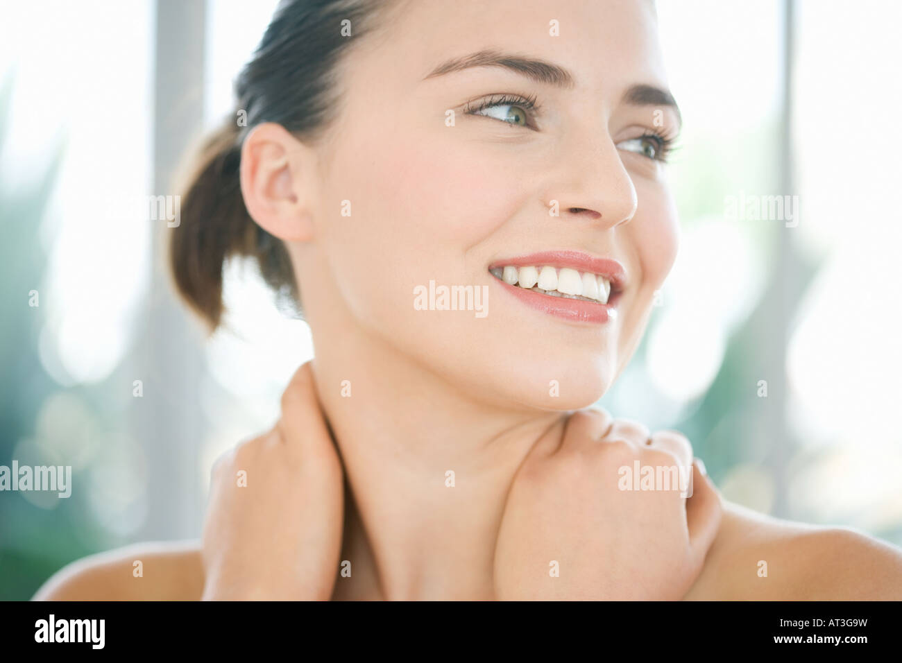 Young woman smiling, hands on neck and head turned to one side Stock ...