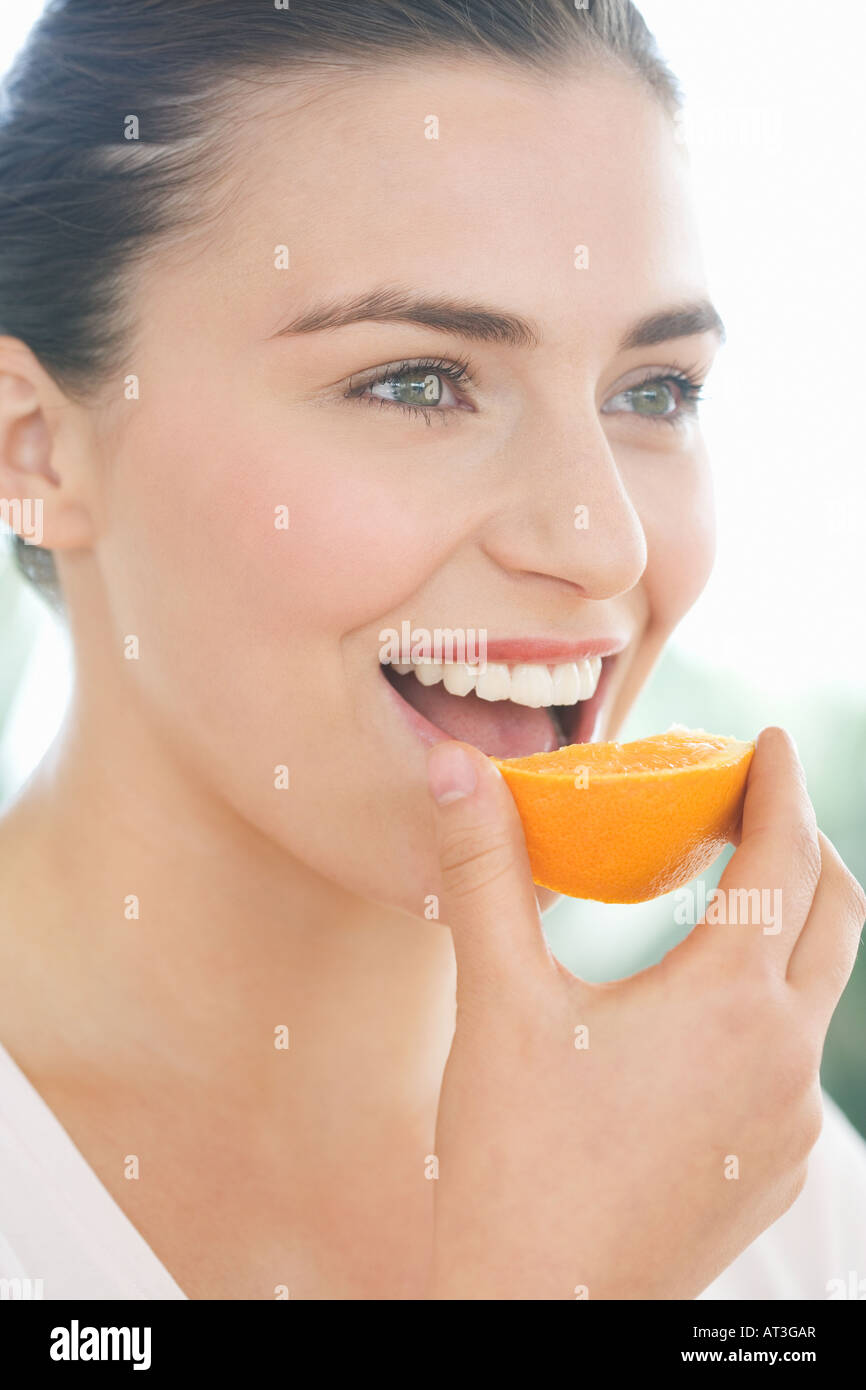 Young woman eating a piece of orange Stock Photo - Alamy