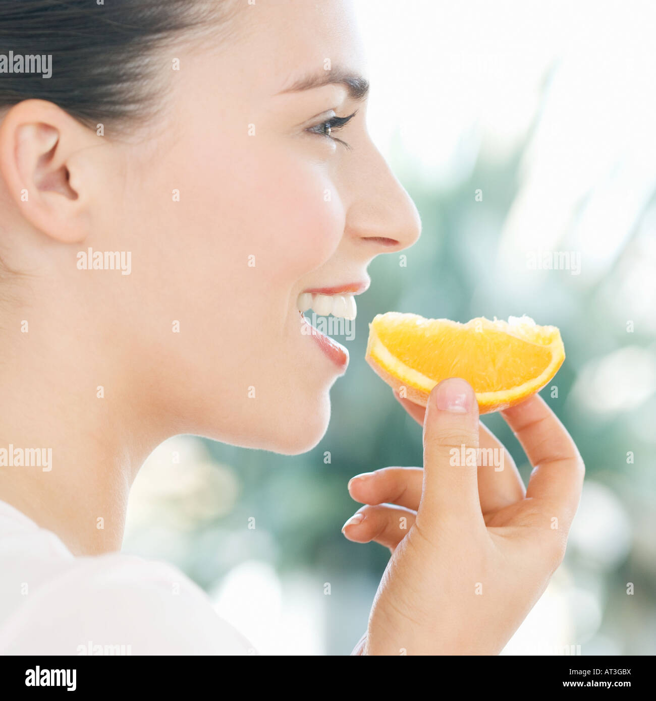 Young woman eating a piece of orange, side view Stock Photo - Alamy