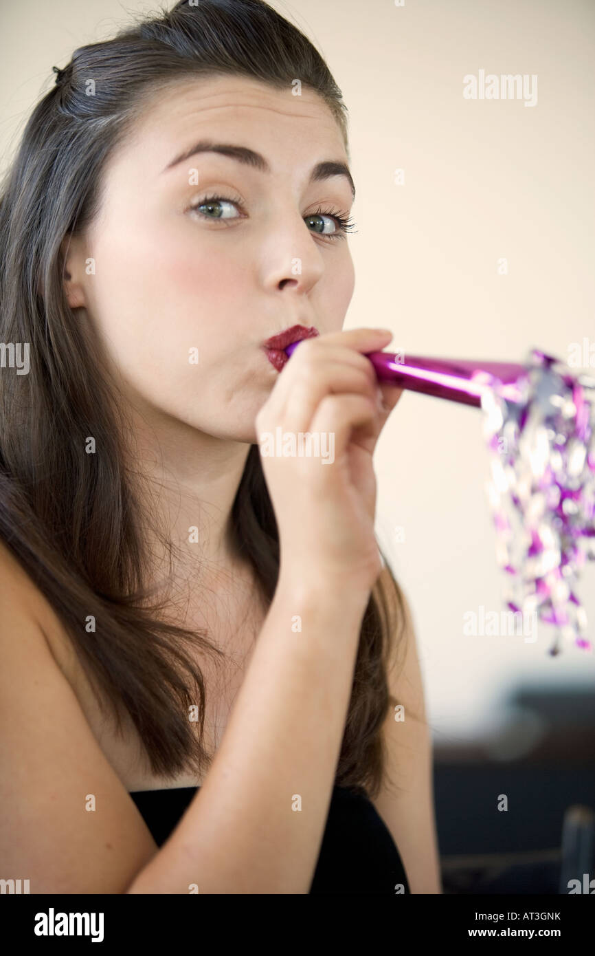 Young woman blowing a party blower Stock Photo - Alamy