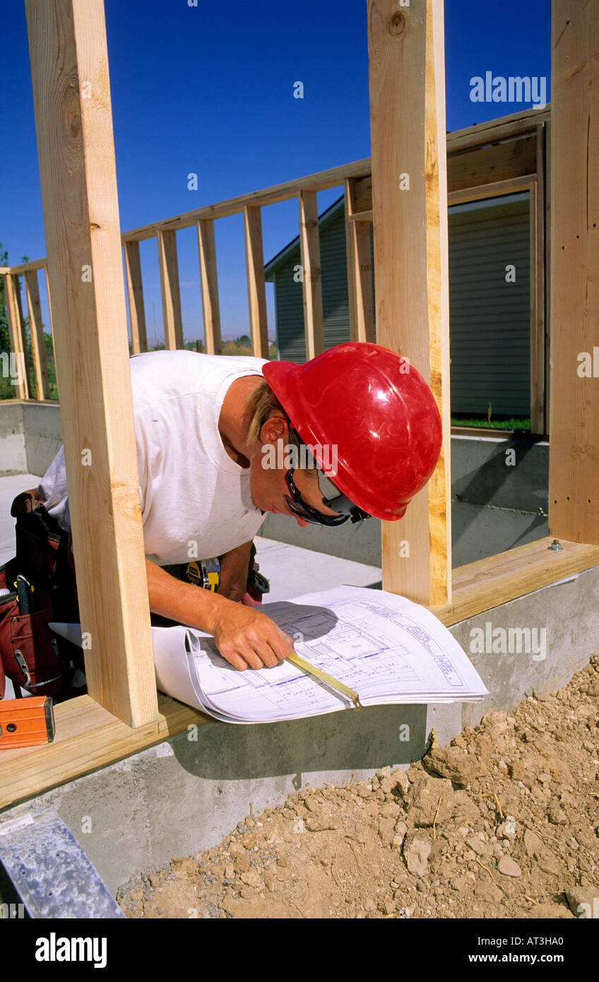A framing carpenter examines building blue prints on a construction ...