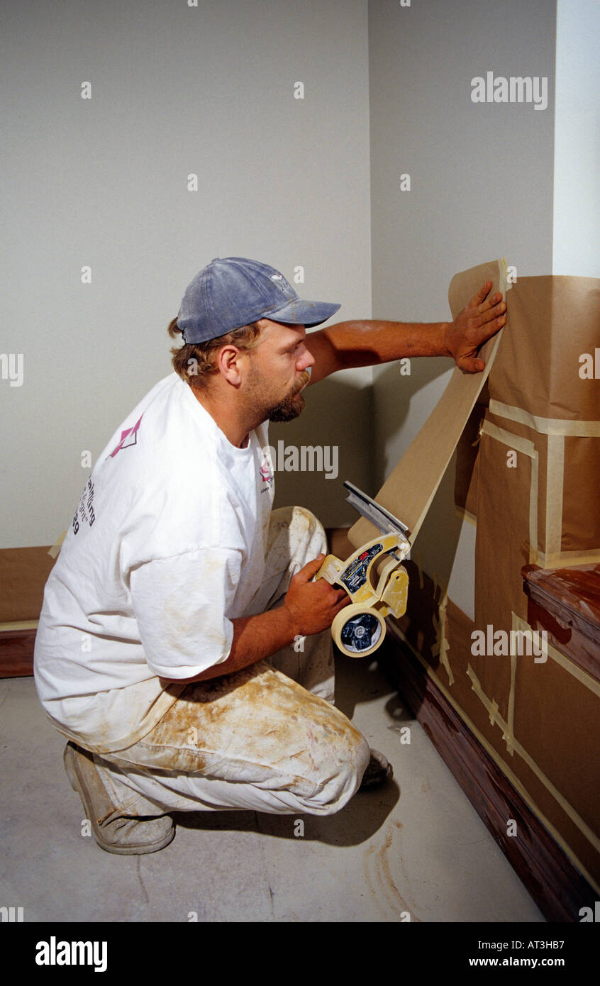 A painter uses a masking tape applicator to mask off portions of the ...
