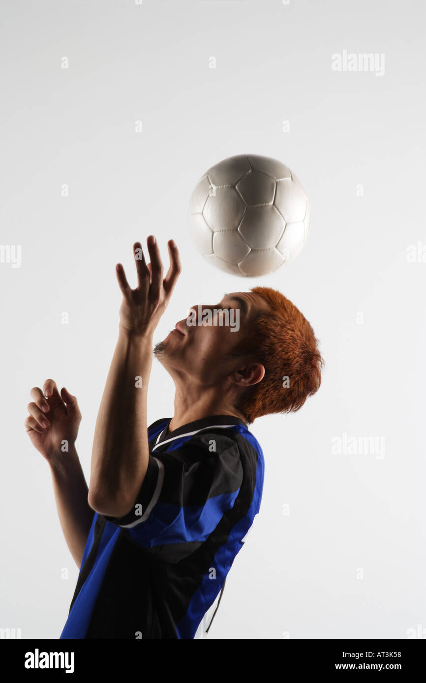 Soccer player juggling ball on head Stock Photo - Alamy