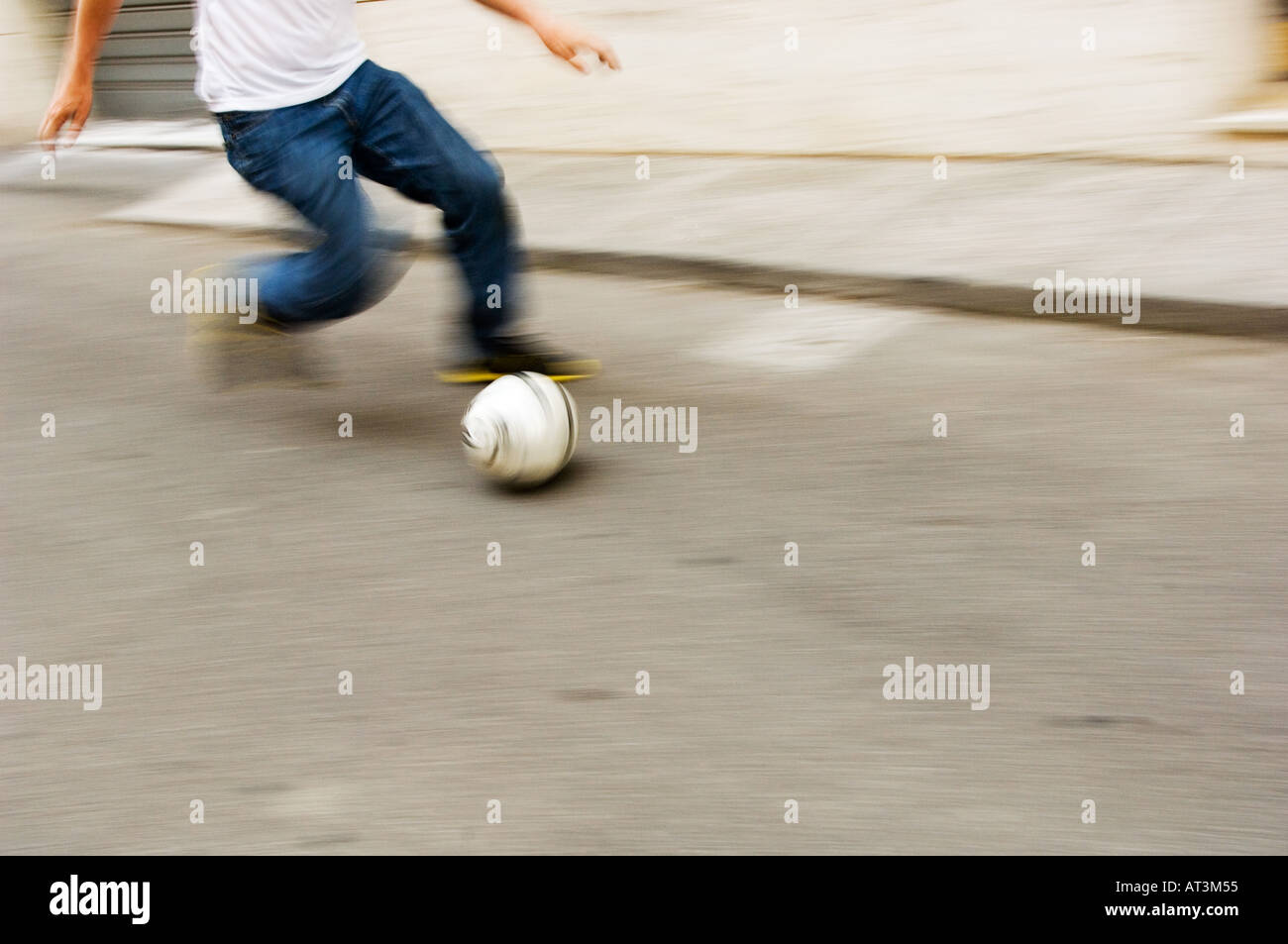 Man running with soccer ball in street Stock Photo - Alamy