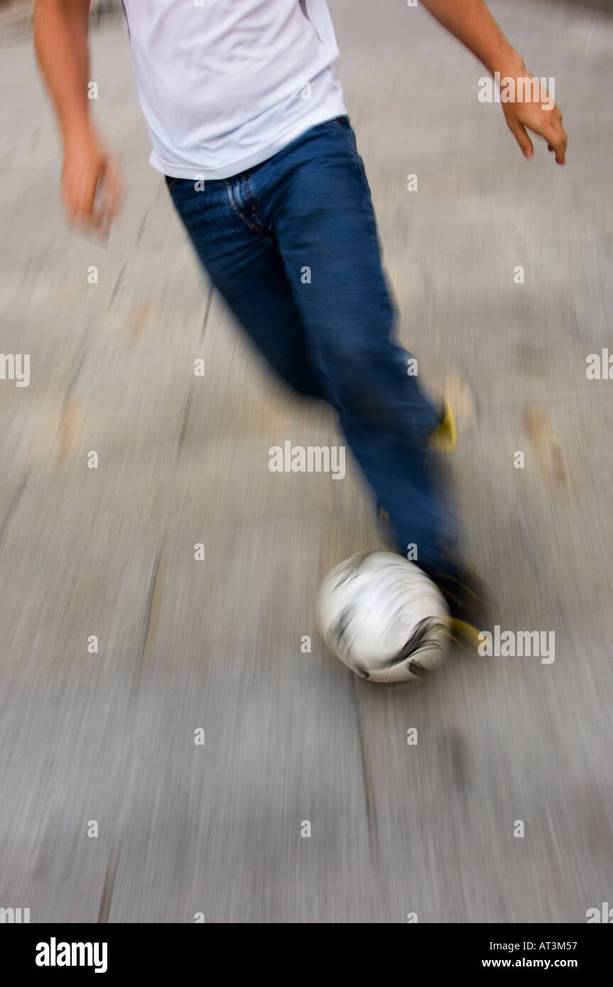 Man dribbling soccer ball in street Stock Photo - Alamy