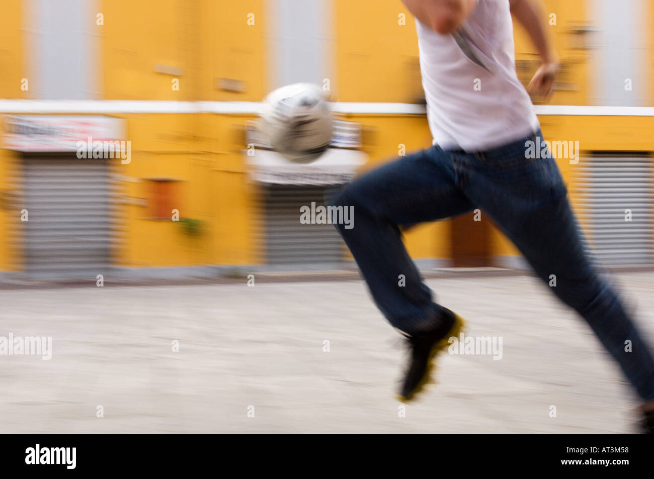 Man running with soccer ball in street Stock Photo - Alamy