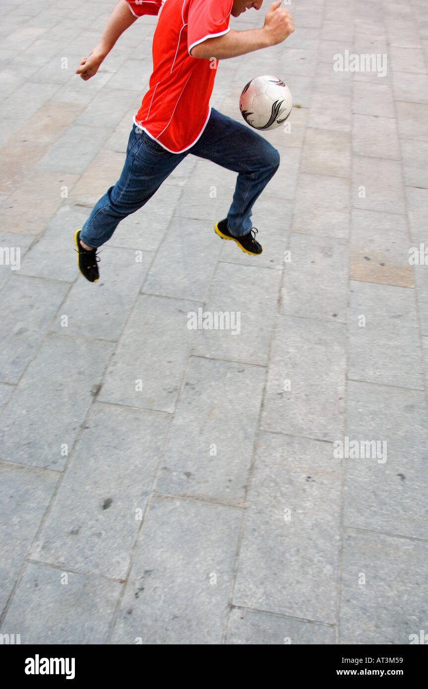 Man running with soccer ball in town square Stock Photo - Alamy