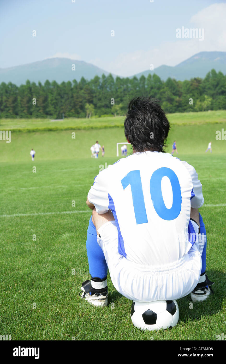 Soccer player sitting on ball Stock Photo - Alamy