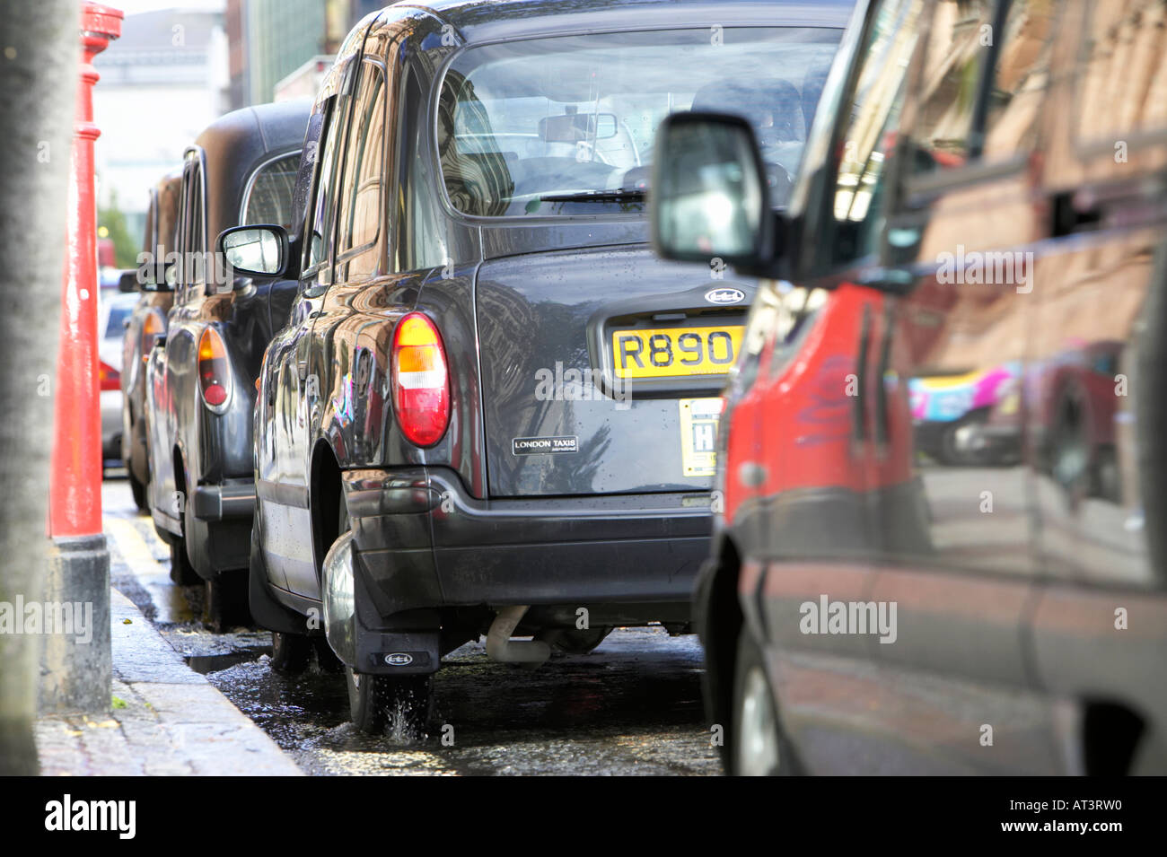 waiting row of black london hackey carriage taxis on a rank next to the ...