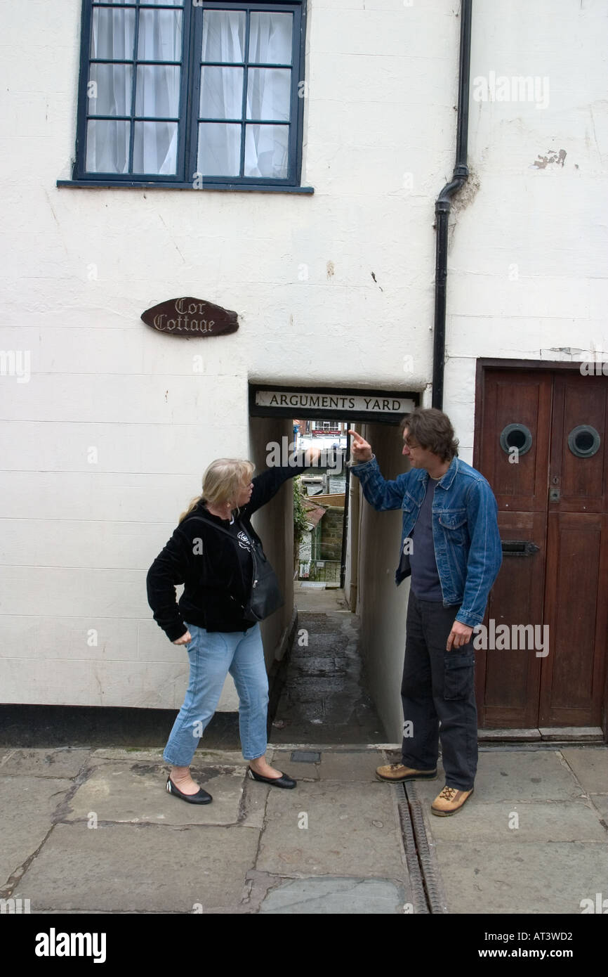 Two people arguing and pointing at eachother in front of a street sign ...