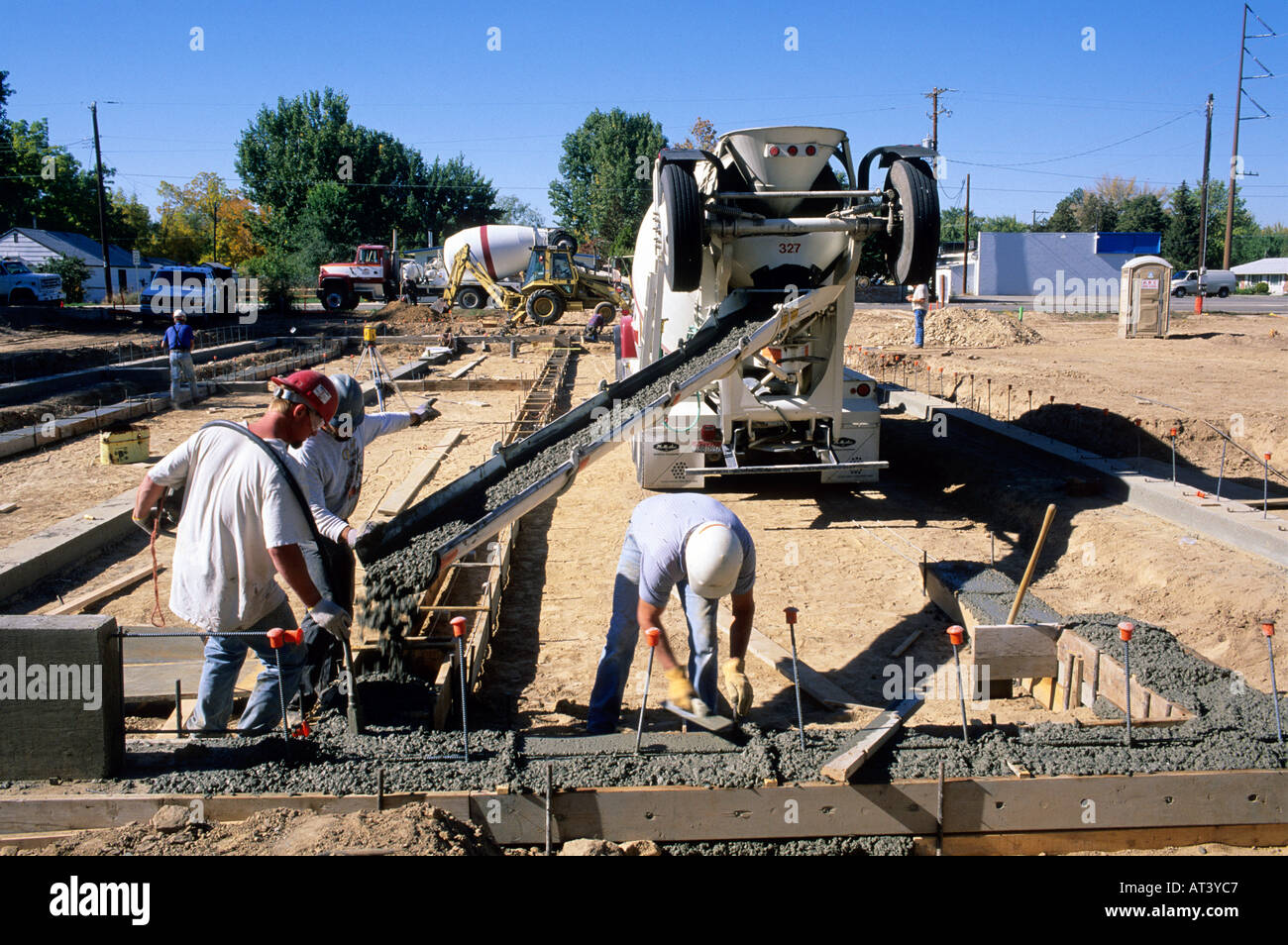 Workers pour ready-mix concrete footings for a new home foundation ...