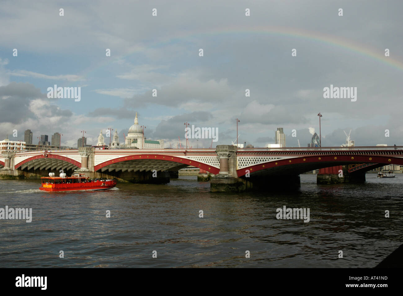 River Thames with red boat passing under Blackfriars Bridge and rainbow ...