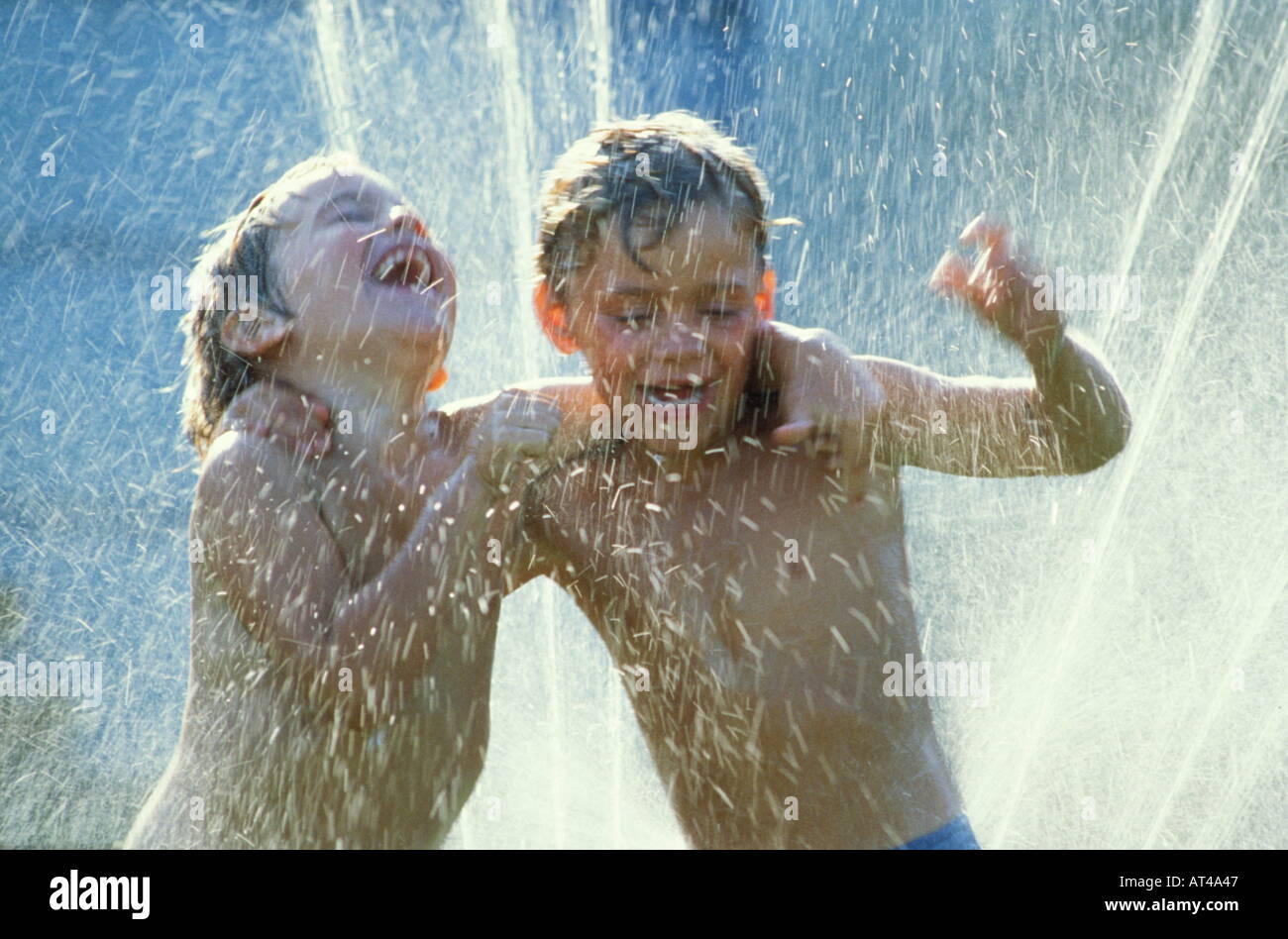 Kids Playing in a Sprinkler Stock Photo - Alamy
