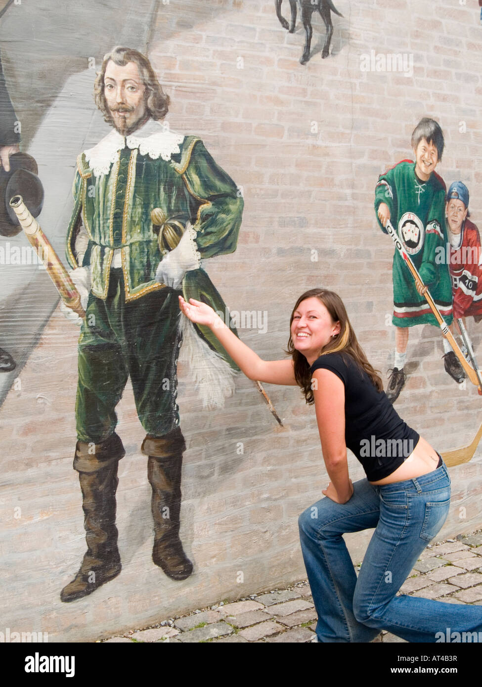 A woman interacting with a character in the Quebec Mural, situated by ...