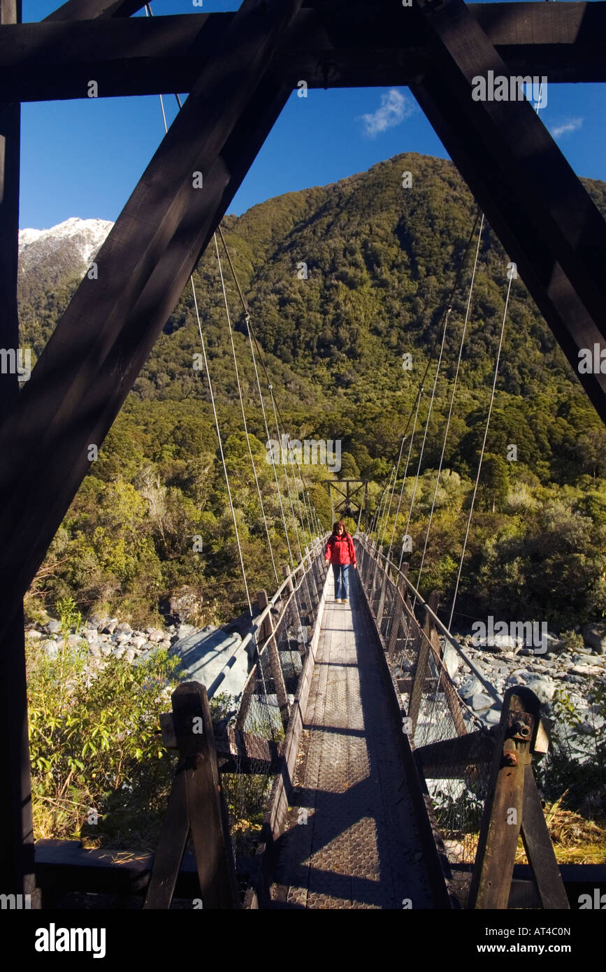 A walker crosses a swing bridge over a river in New Zealand Stock Photo ...