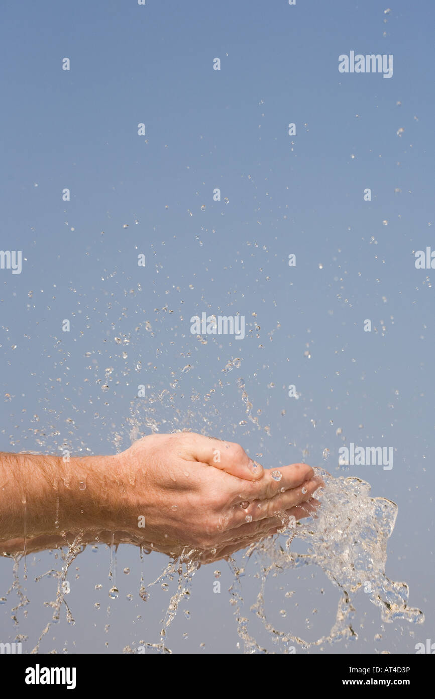Catching water into cupped hands in front of a blue sky Stock Photo - Alamy