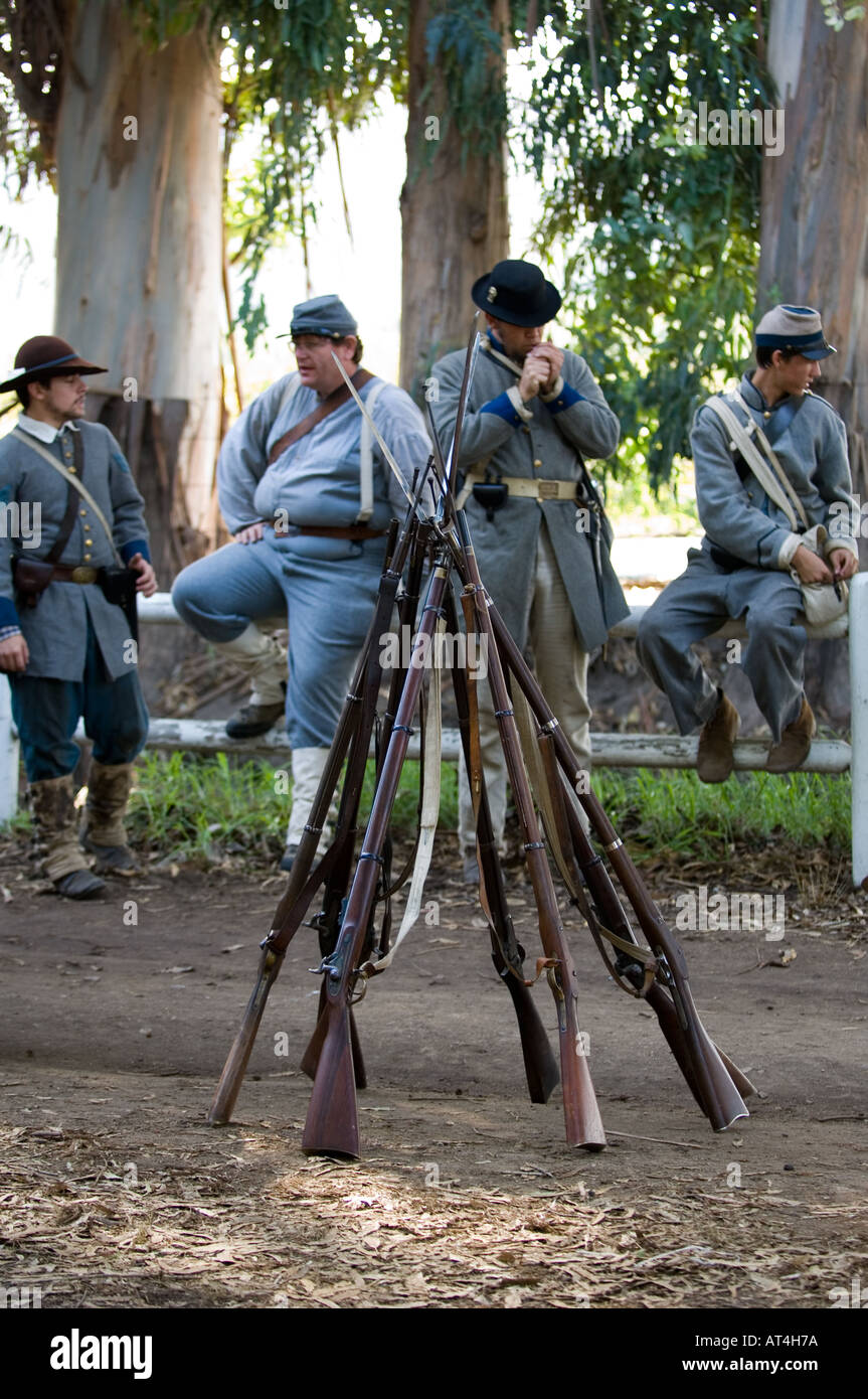 Soldiers resting at Civil War reenactment event rifles with mounted ...