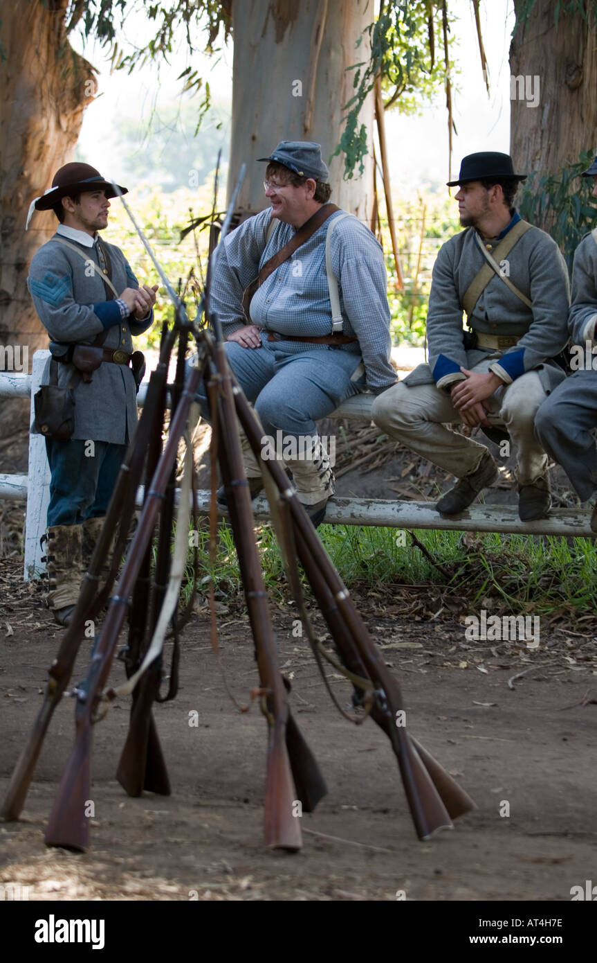 Soldiers resting at Civil War reenactment event rifles with mounted ...