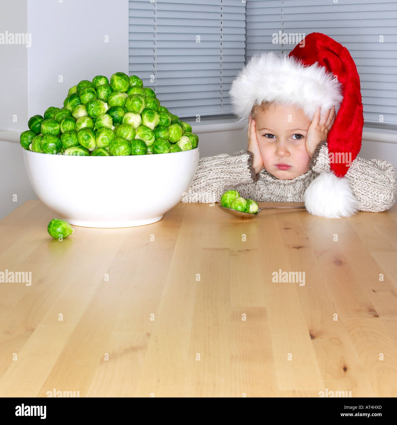young boy sitting with a large bowl of sprouts with a Christmas hat on ...