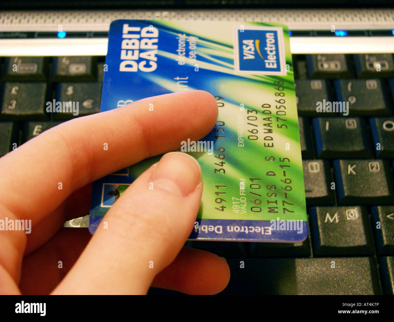 A Hand Holding a Debit Card over a Computer Keyboard Stock Photo - Alamy