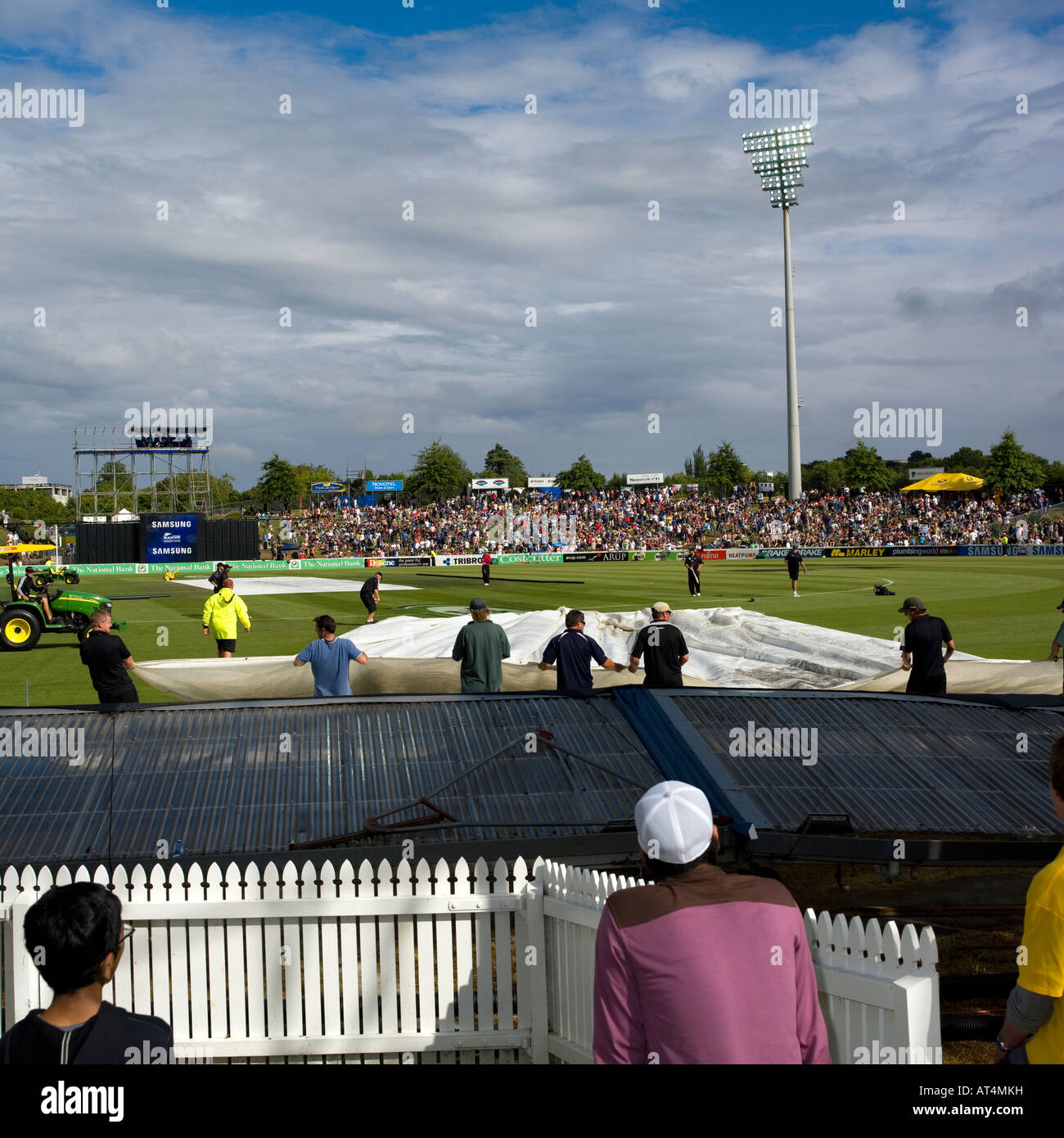 Men pulling of cricket covers being watched by crowd Stock Photo - Alamy