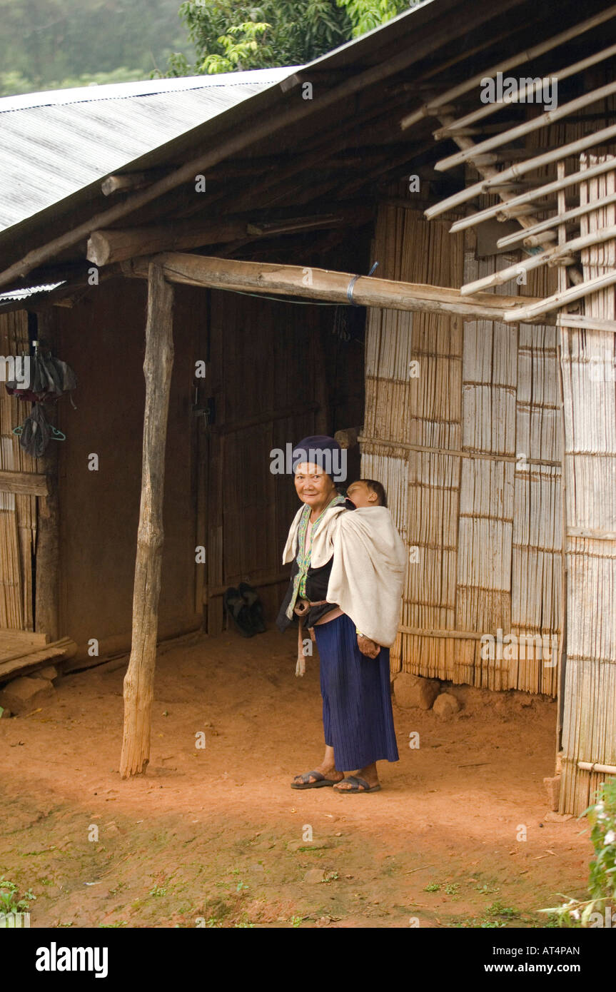 Woman with a child on her back outside a hut in the Hmong village Baan ...
