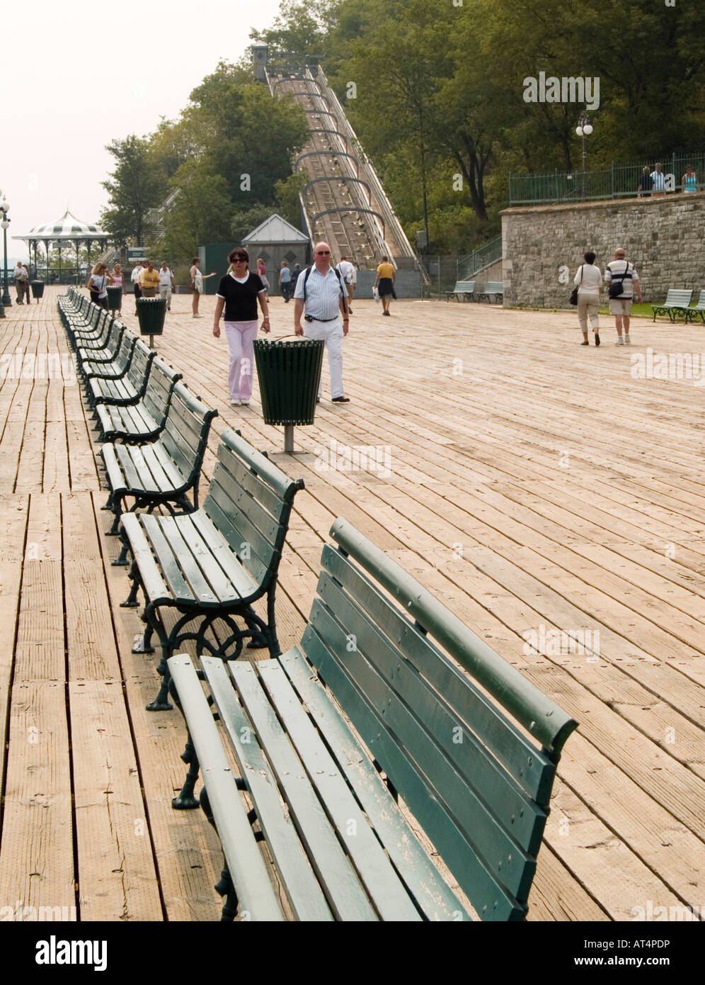 A row of benches, and people walking along the boardwalk of the ...